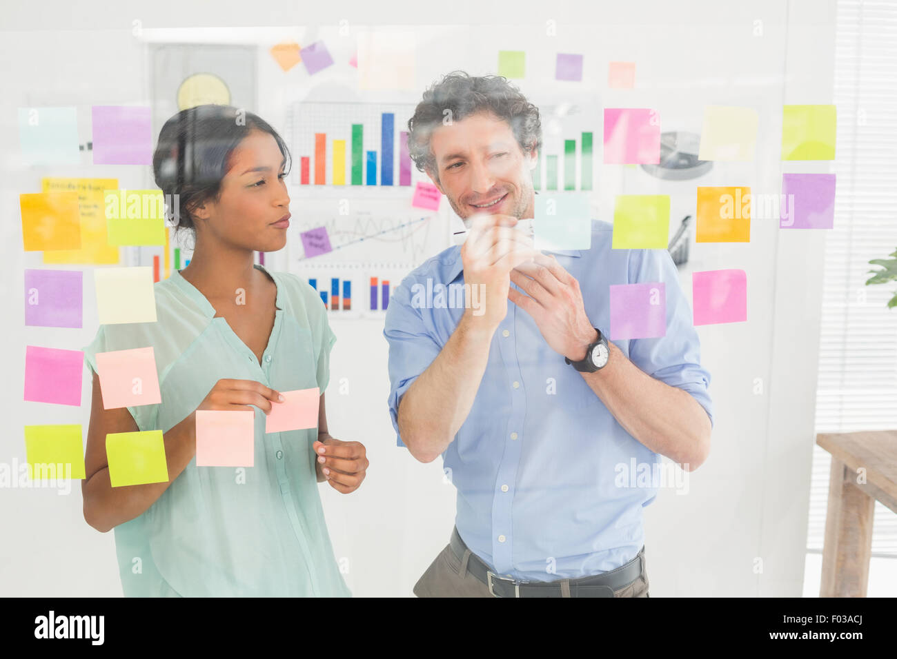Puzzled business team looking post its on the wall Stock Photo - Alamy