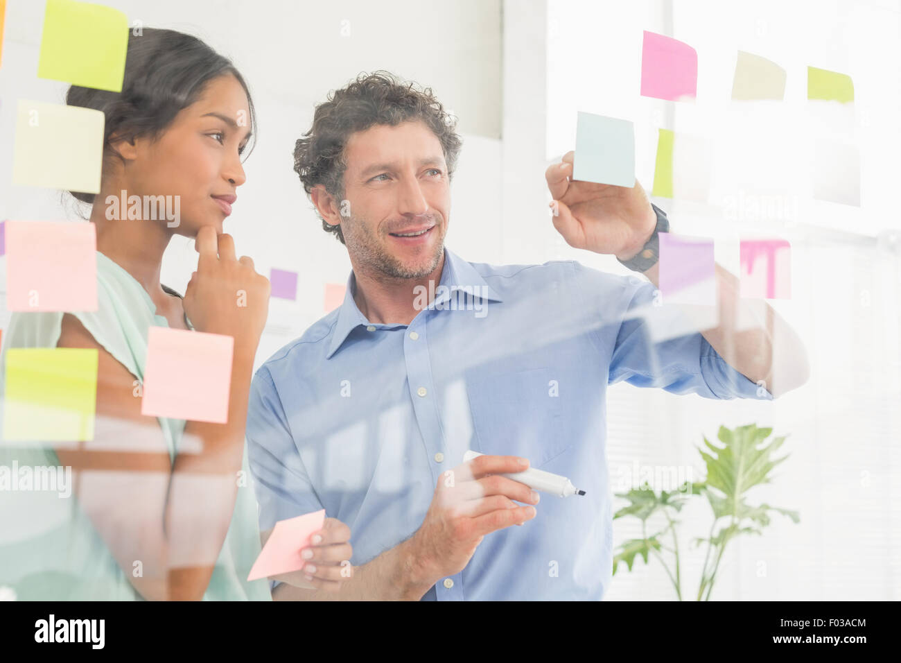 Puzzled business team looking post its on the wall Stock Photo - Alamy