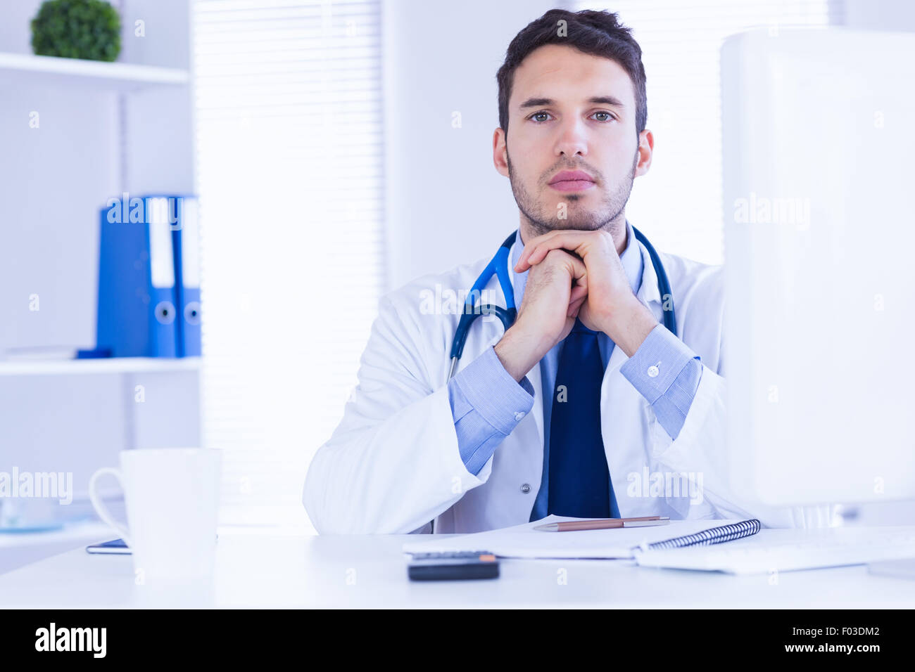 Portrait of doctor looking at camera with hands folded Stock Photo - Alamy