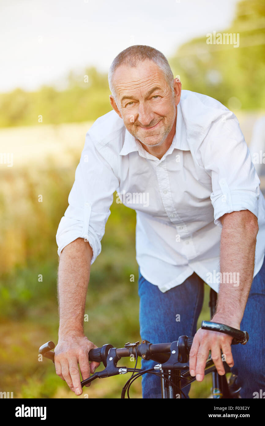 Smiling old man riding bike in summer in nature Stock Photo - Alamy