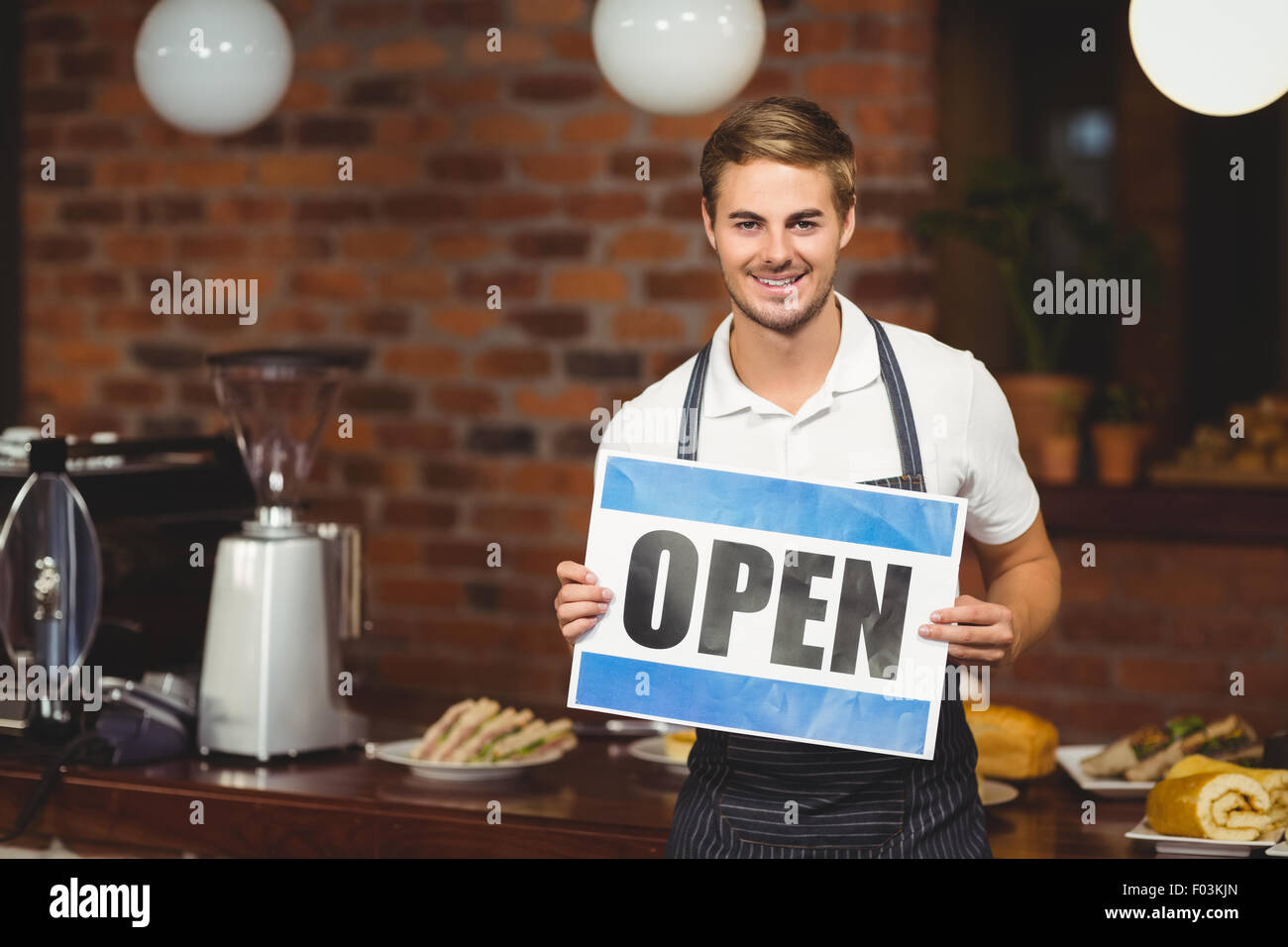 Handsome waiter presenting open sign Stock Photo - Alamy