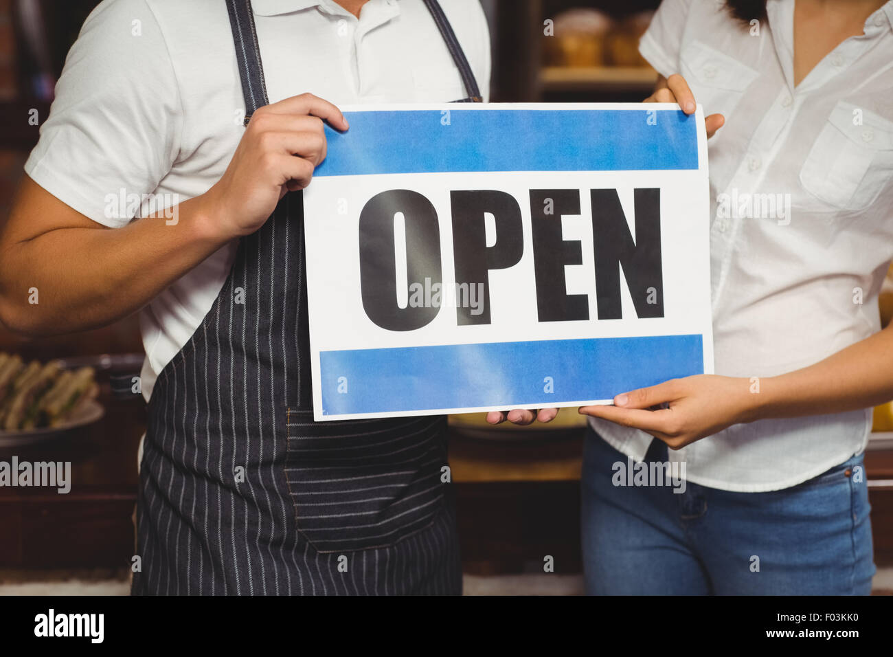 Waiter and waitress posing with open sign Stock Photo - Alamy