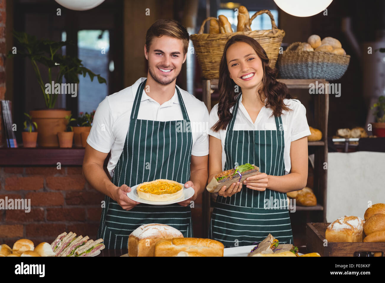 Smiling co-workers showing sandwich and pie Stock Photo - Alamy