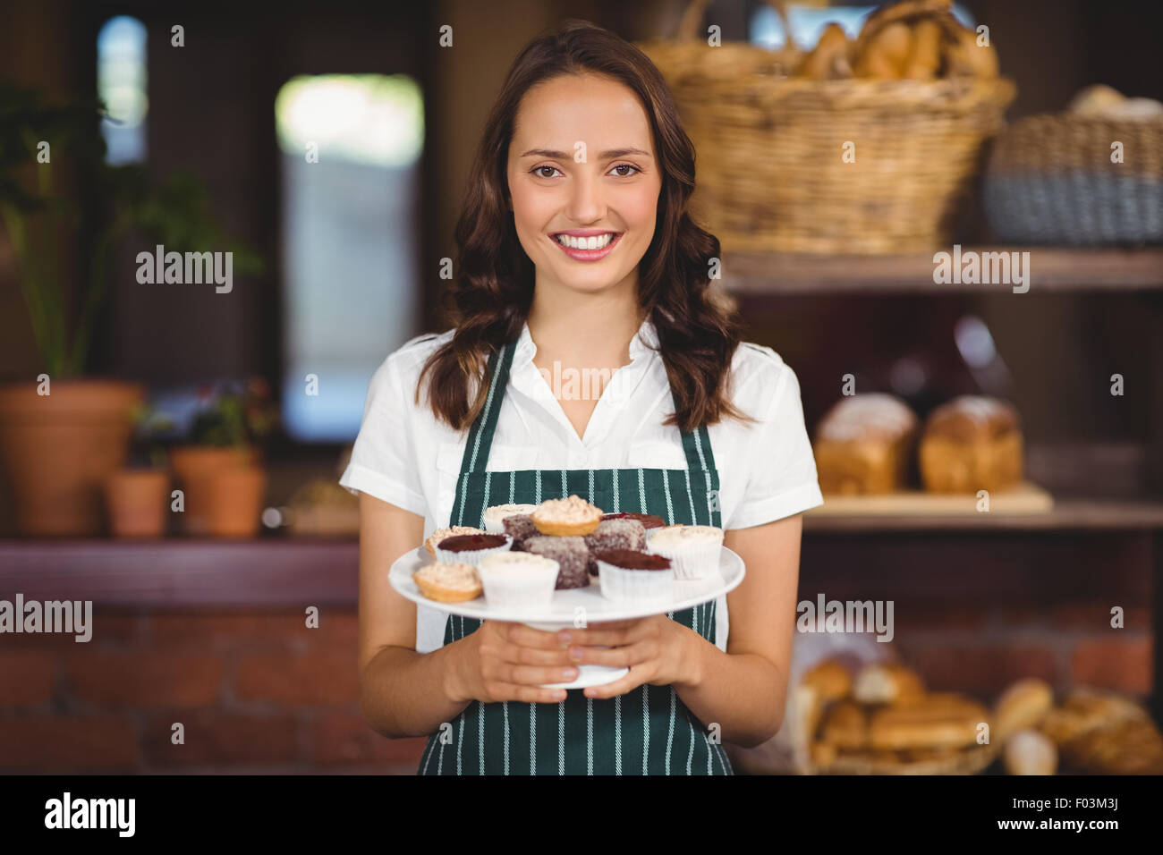 Pretty waitress showing a plate of cupcakes Stock Photo - Alamy