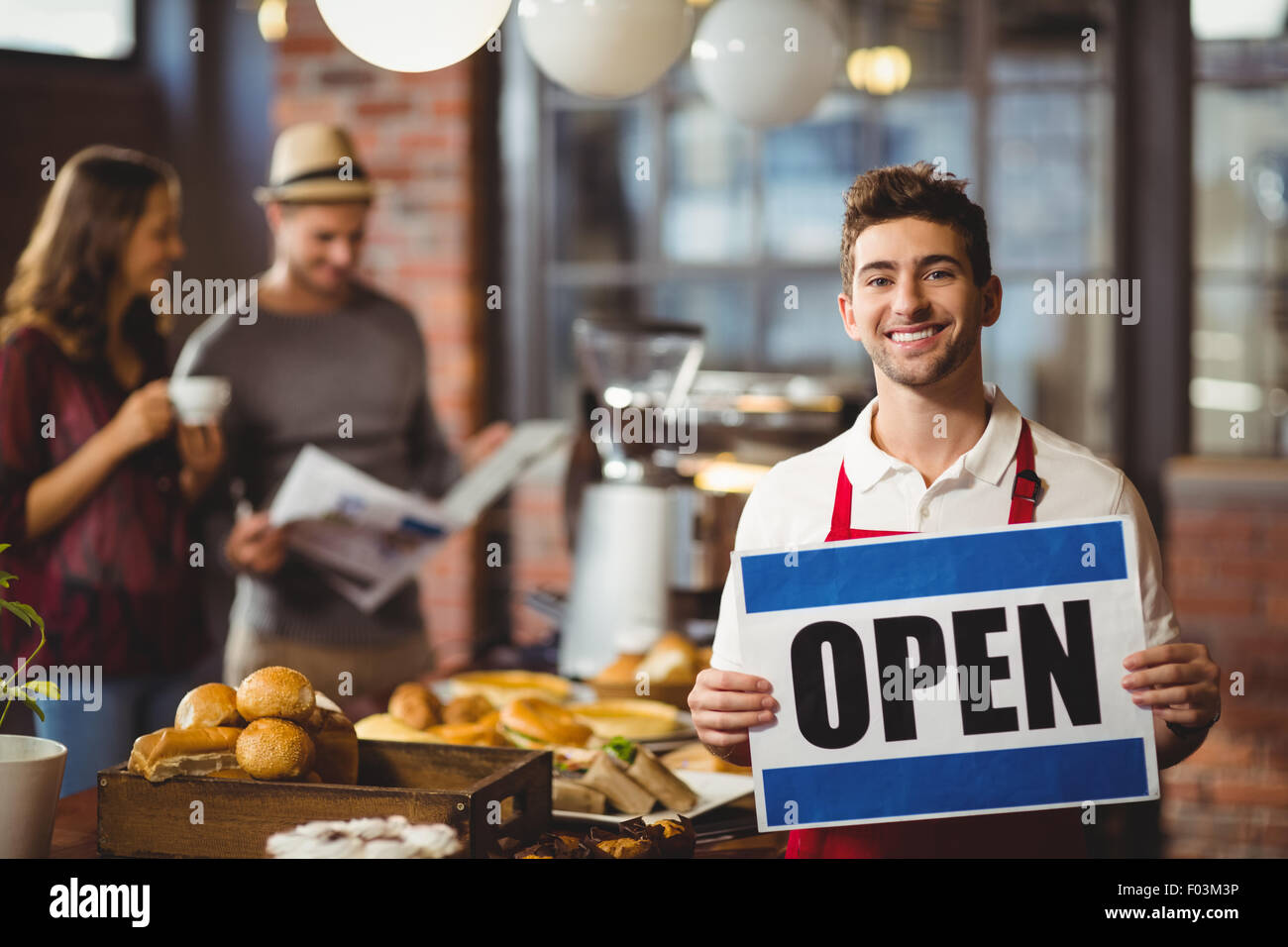Smiling waiter posing with open sign Stock Photo - Alamy