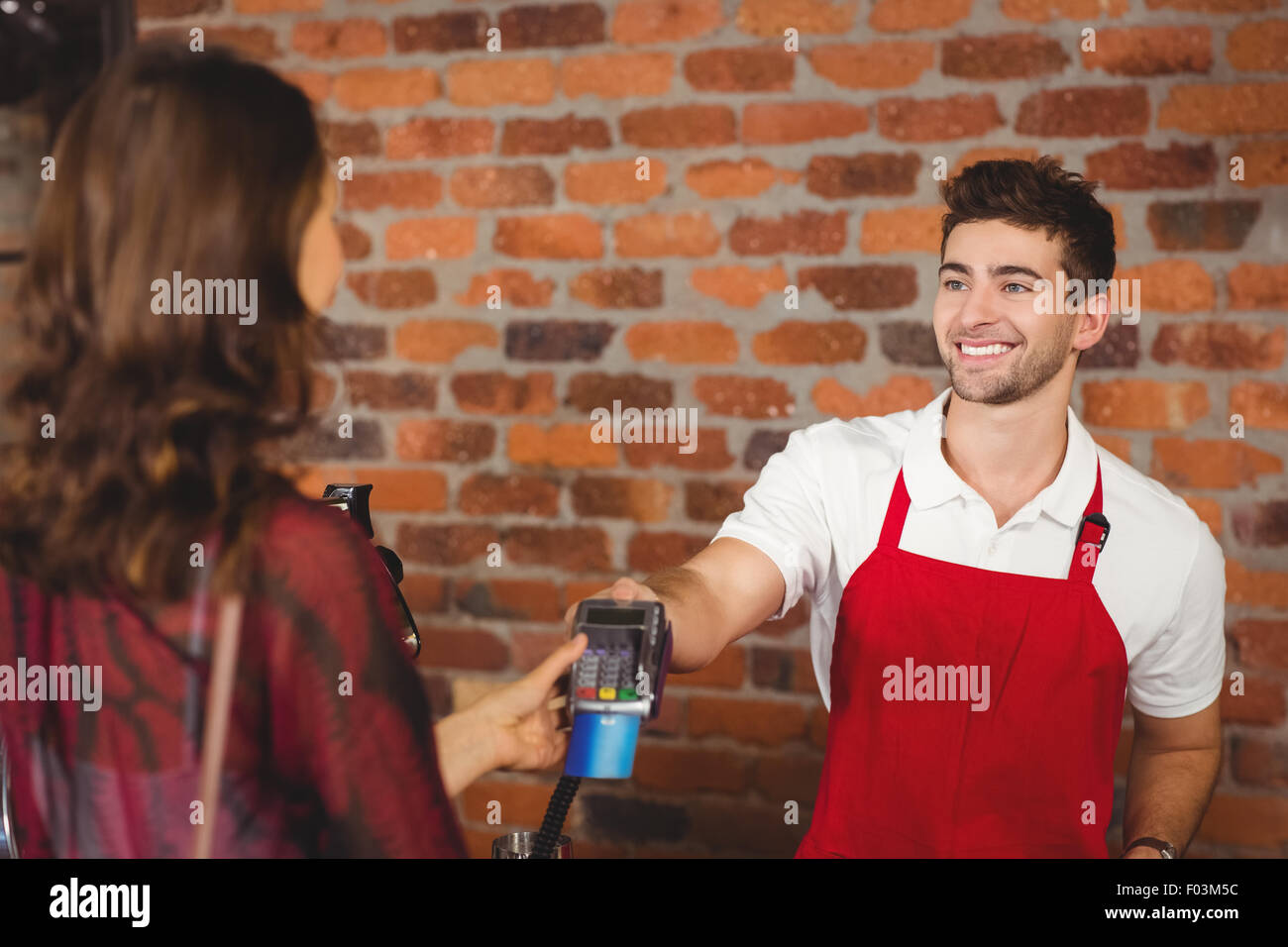 Smiling waiter handing a pin terminal Stock Photo - Alamy