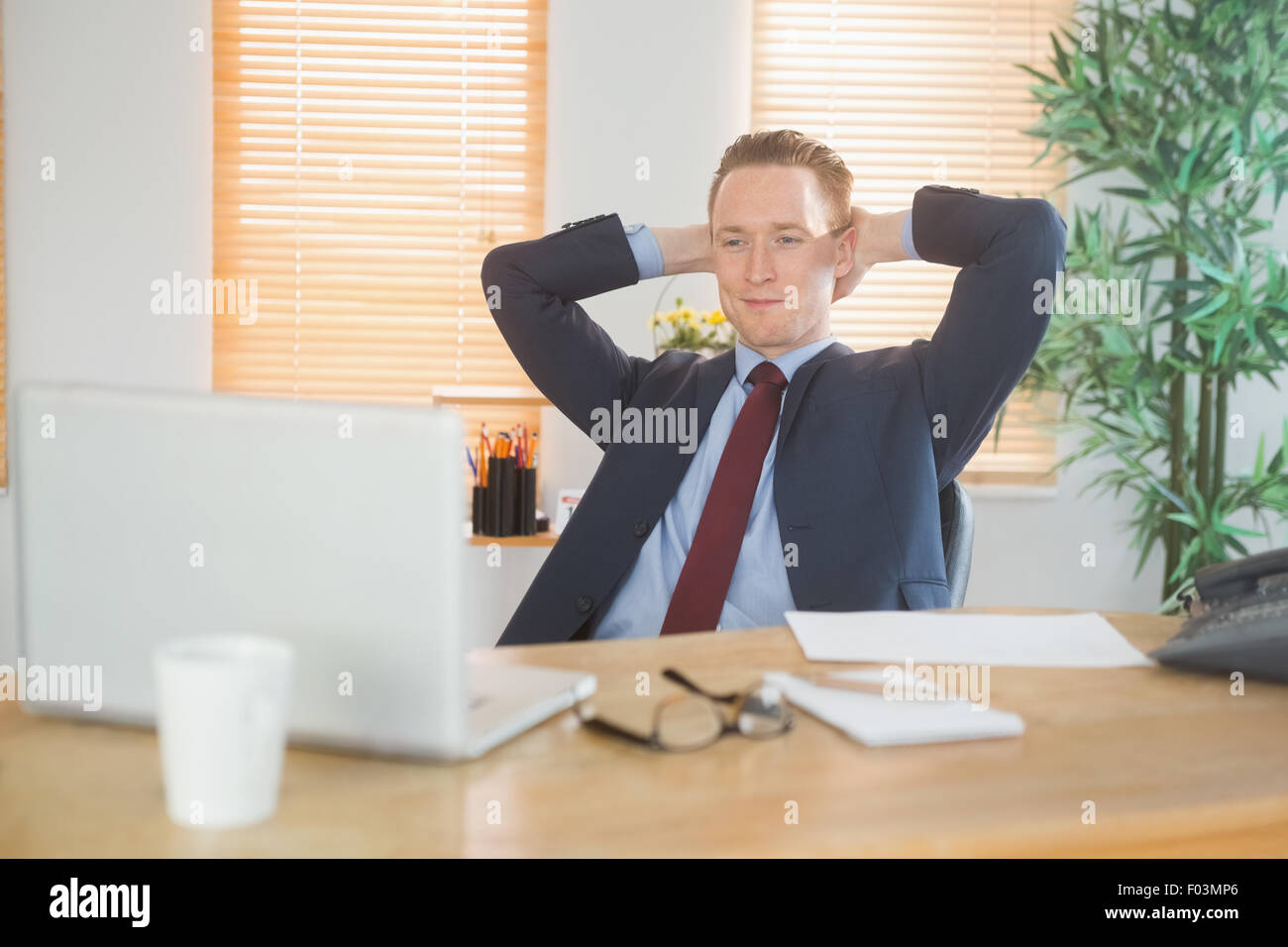 Relaxed businessman sitting back at desk Stock Photo - Alamy