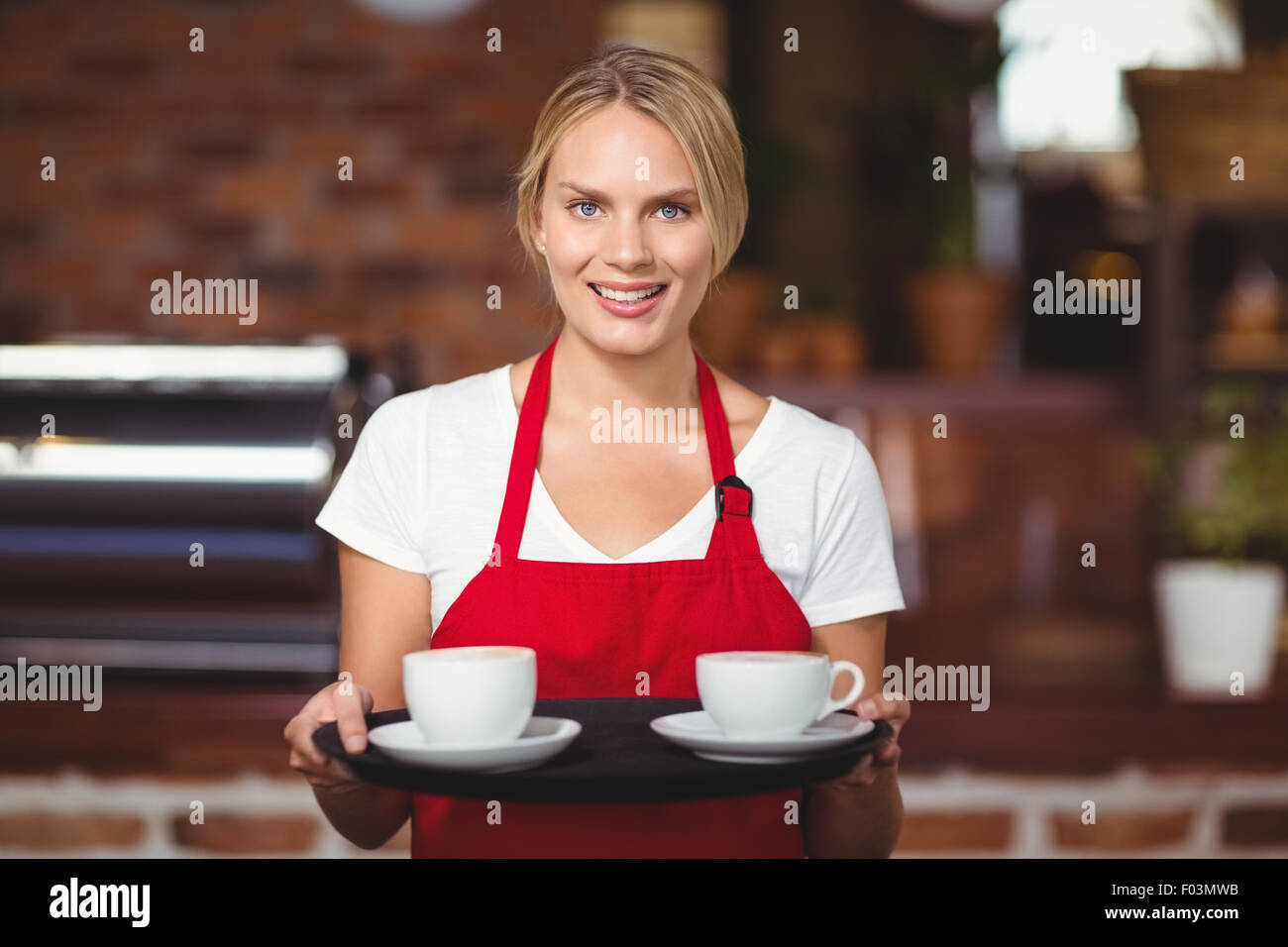 Pretty waitress holding a tray with coffees Stock Photo - Alamy