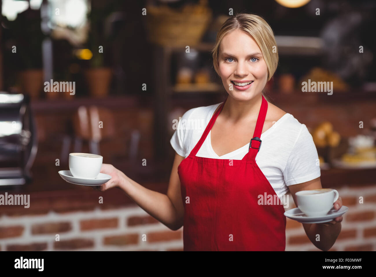 Pretty waitress holding two cups of coffees Stock Photo - Alamy