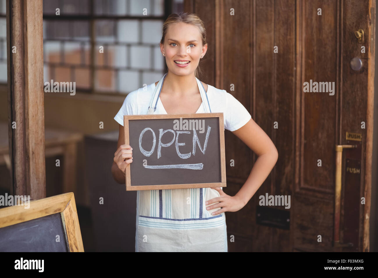 Smiling waitress showing chalkboard with open sign Stock Photo - Alamy