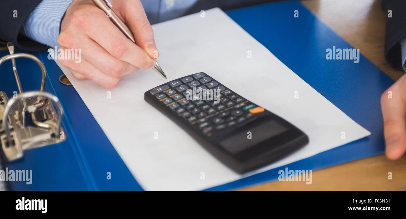 Businessman using a calculator and writing Stock Photo - Alamy