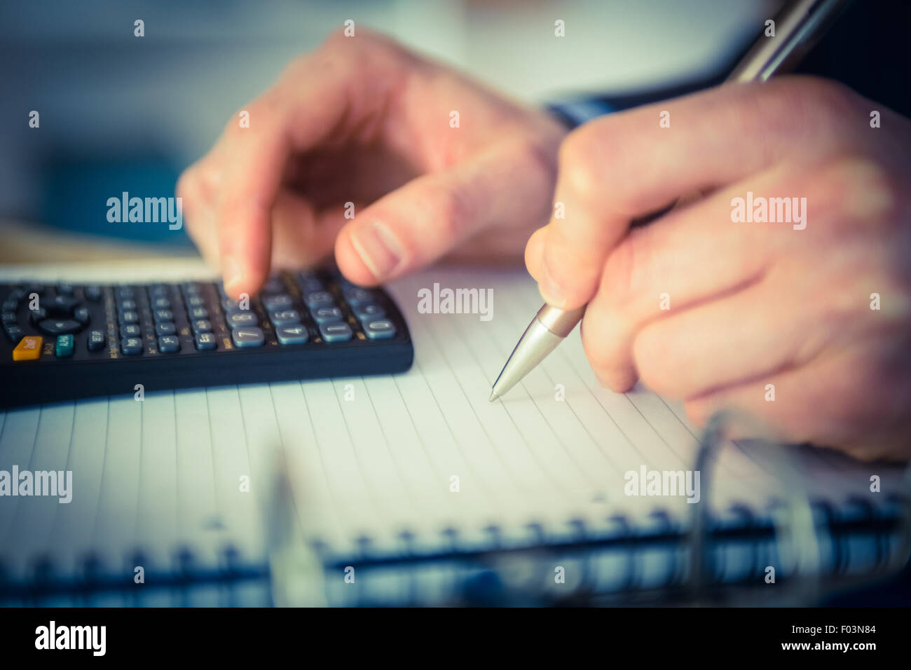 Businessman using a calculator and writing Stock Photo - Alamy