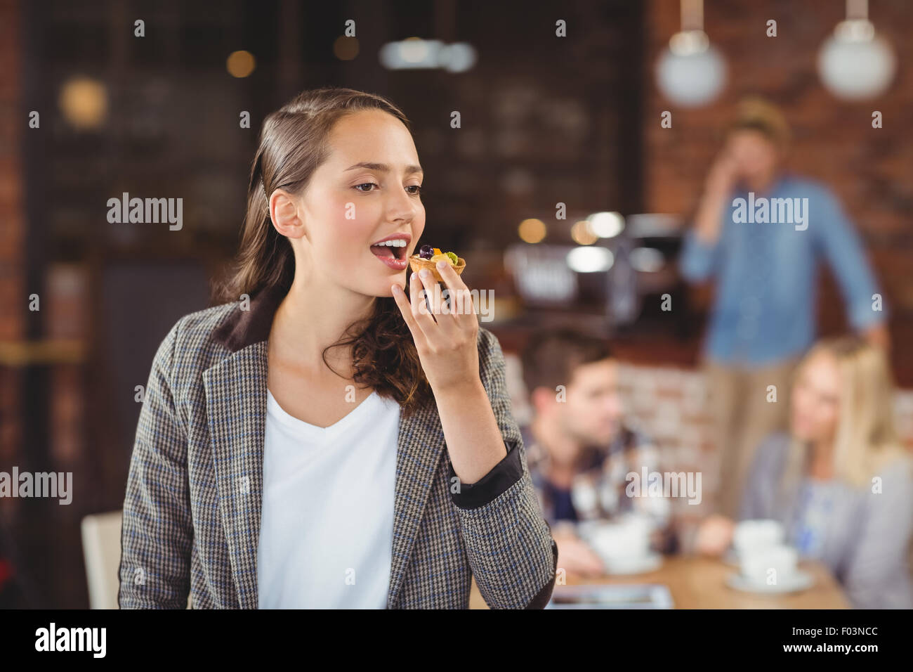 Smiling young woman eating muffin Stock Photo - Alamy