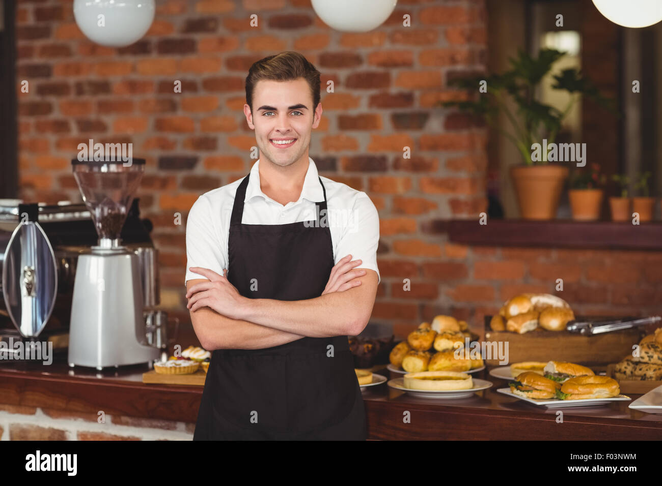 Smiling barista in front of counter with arms crossed Stock Photo - Alamy