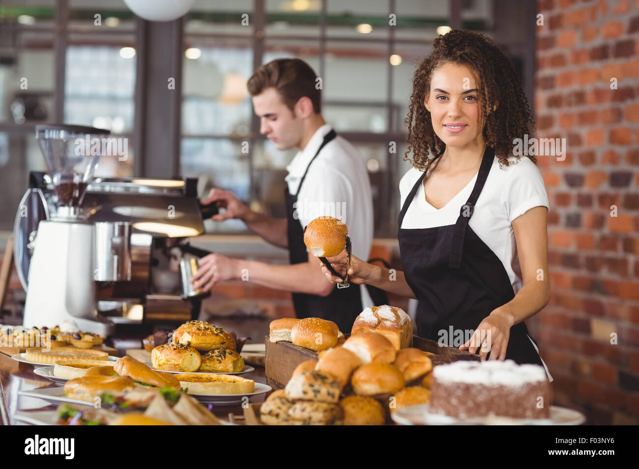 Smiling waitress holding bread roll with tong Stock Photo - Alamy
