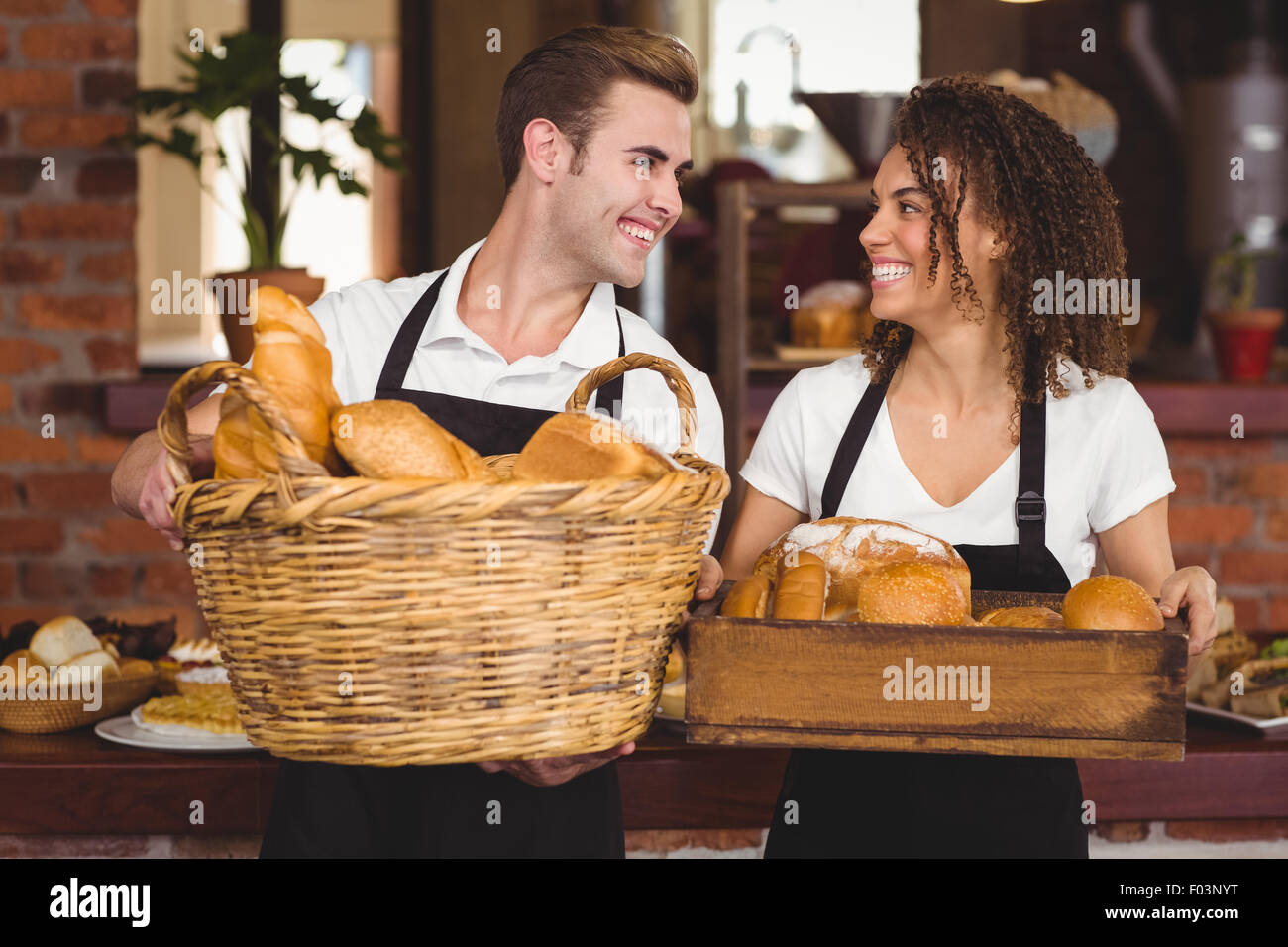 Smiling waiter and waitress holding basket full of bread rolls Stock ...