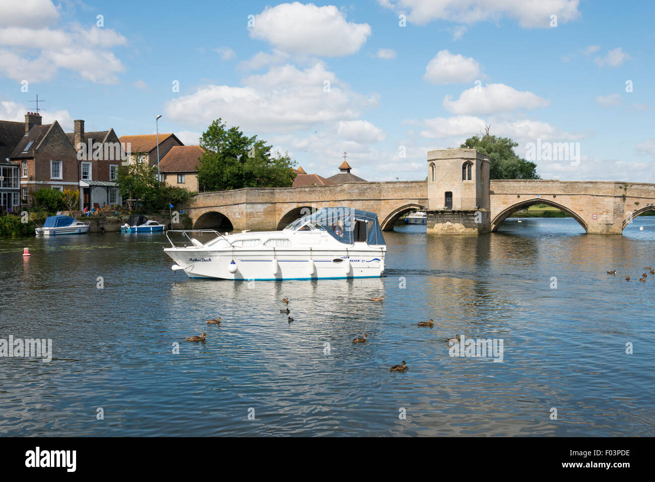 A pleasure boat on the River Great Ouse with the old bridge in the ...