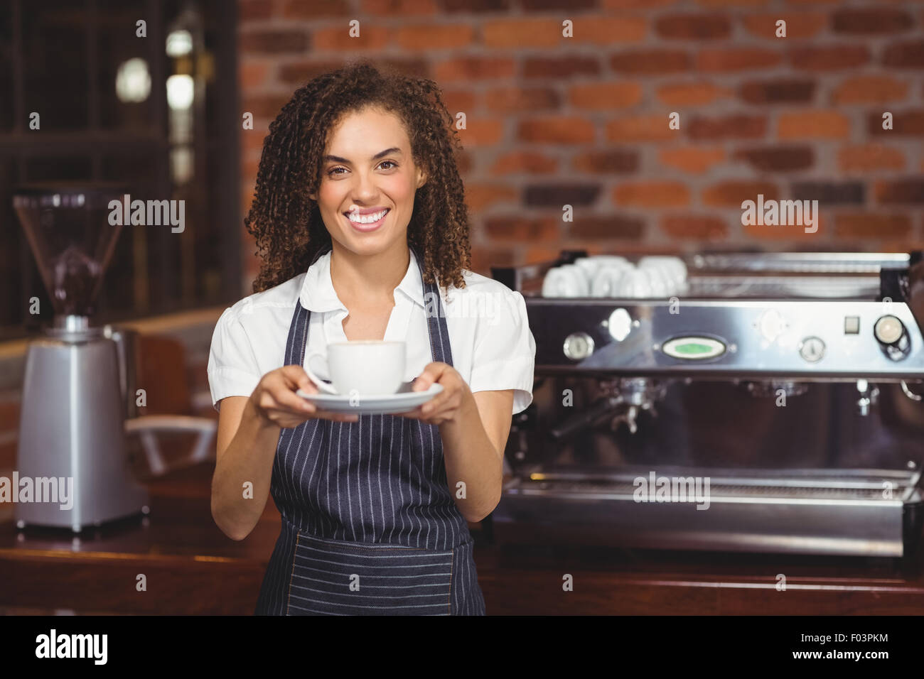 Smiling barista showing cup of coffee Stock Photo - Alamy