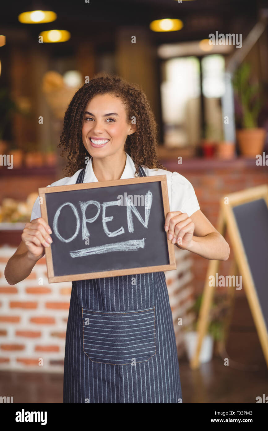 Smiling waitress showing chalkboard with open sign Stock Photo - Alamy
