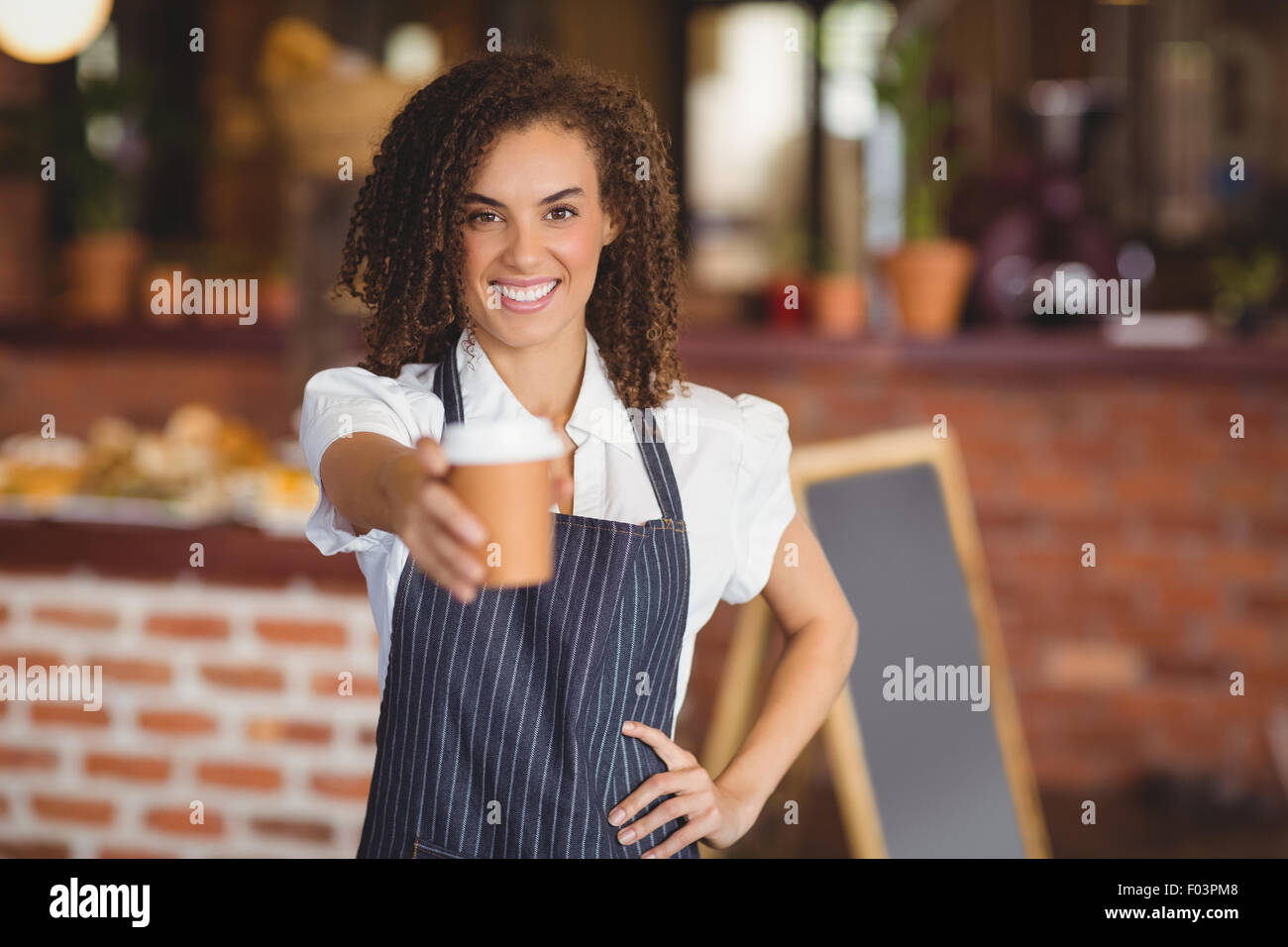 Smiling barista handing a mug of coffee Stock Photo - Alamy
