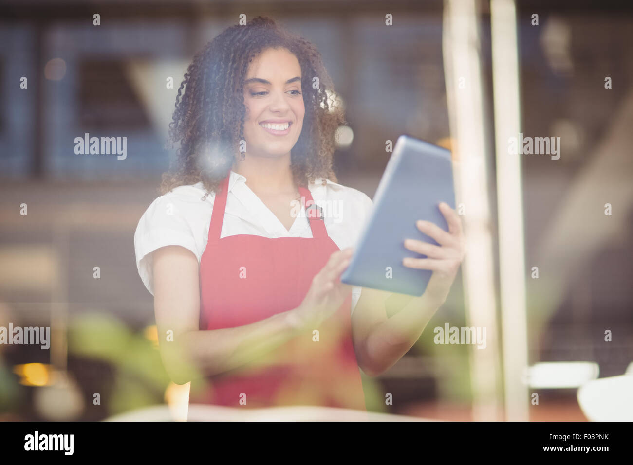Smiling waitress using a digital tablet Stock Photo - Alamy