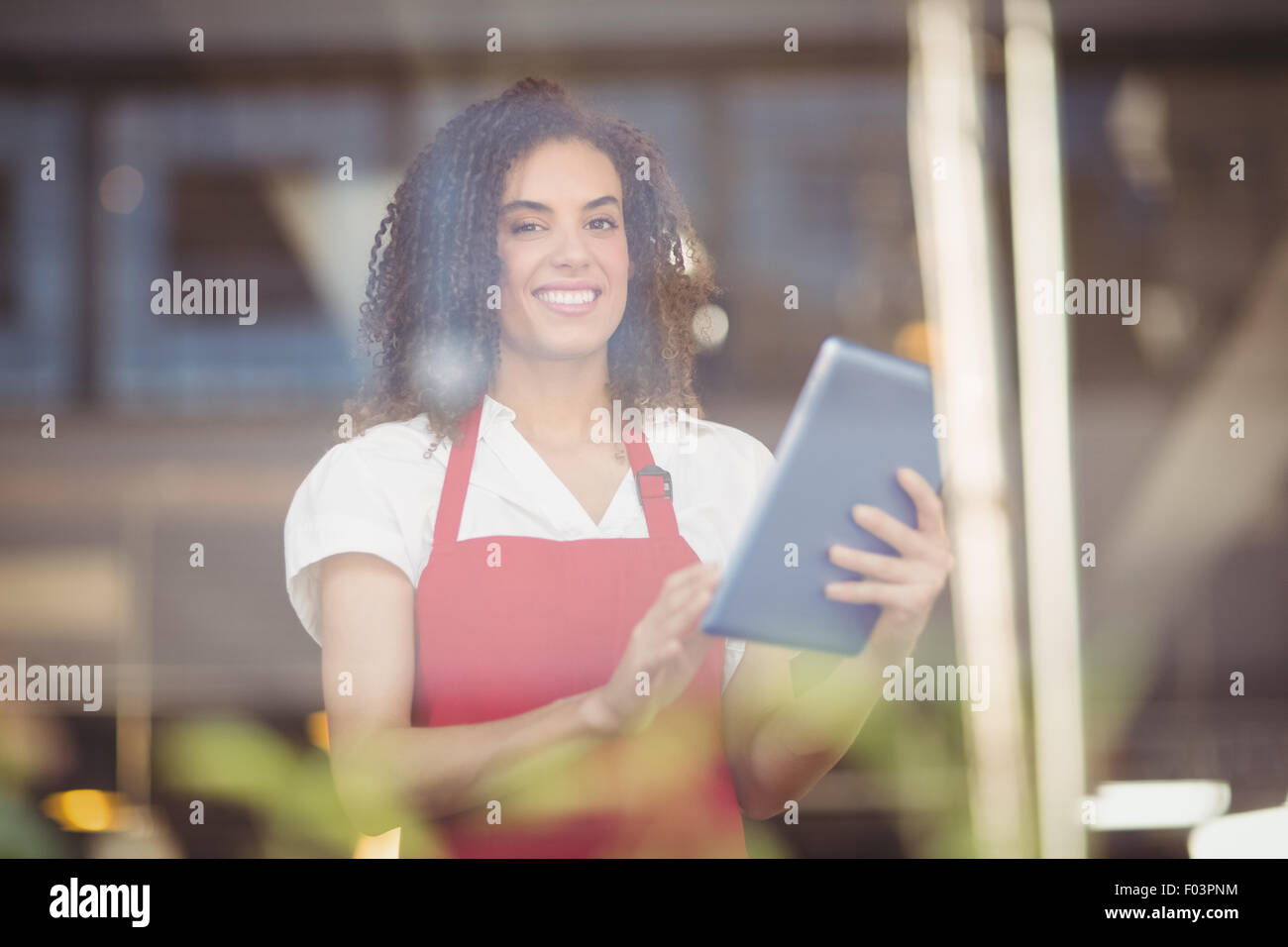 Smiling waitress using a digital tablet Stock Photo - Alamy