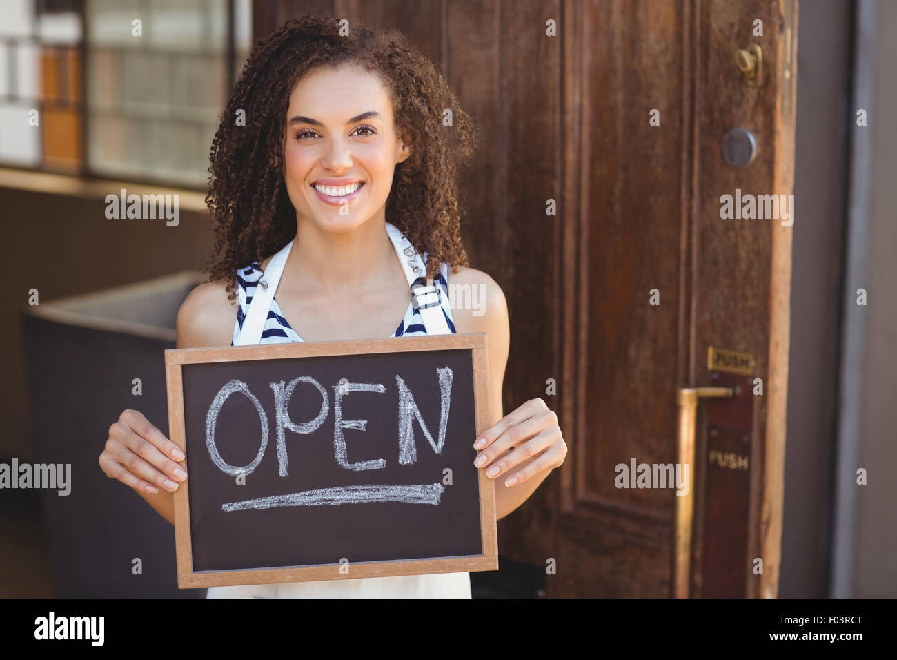 Smiling waitress showing chalkboard with open sign Stock Photo - Alamy
