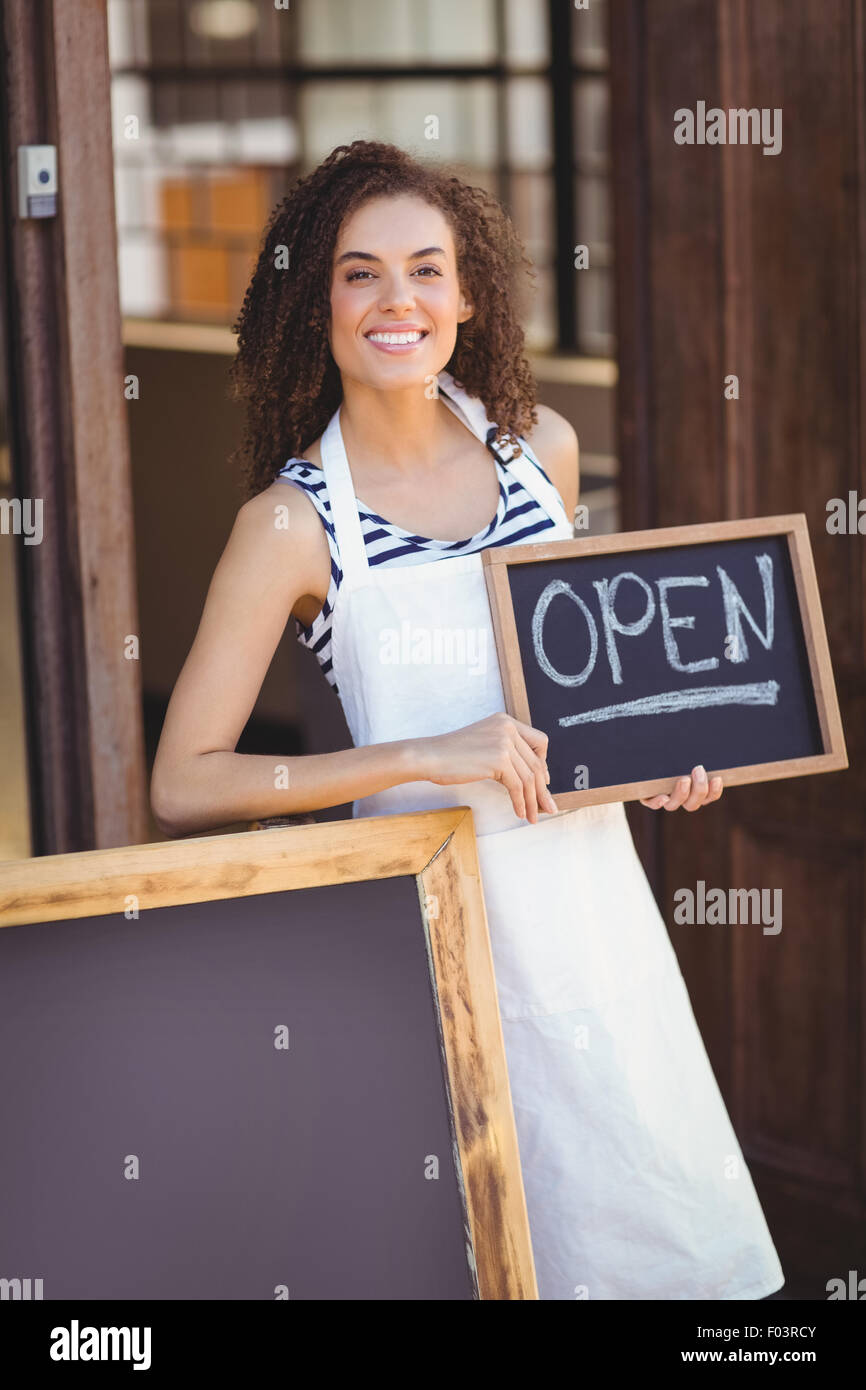 Smiling waitress showing chalkboard with open sign Stock Photo - Alamy