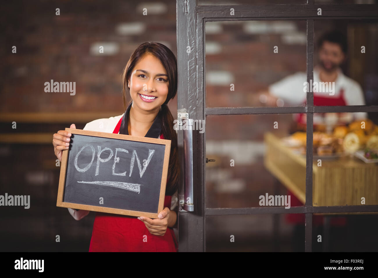 Smiling waitress showing chalkboard with open sign Stock Photo - Alamy