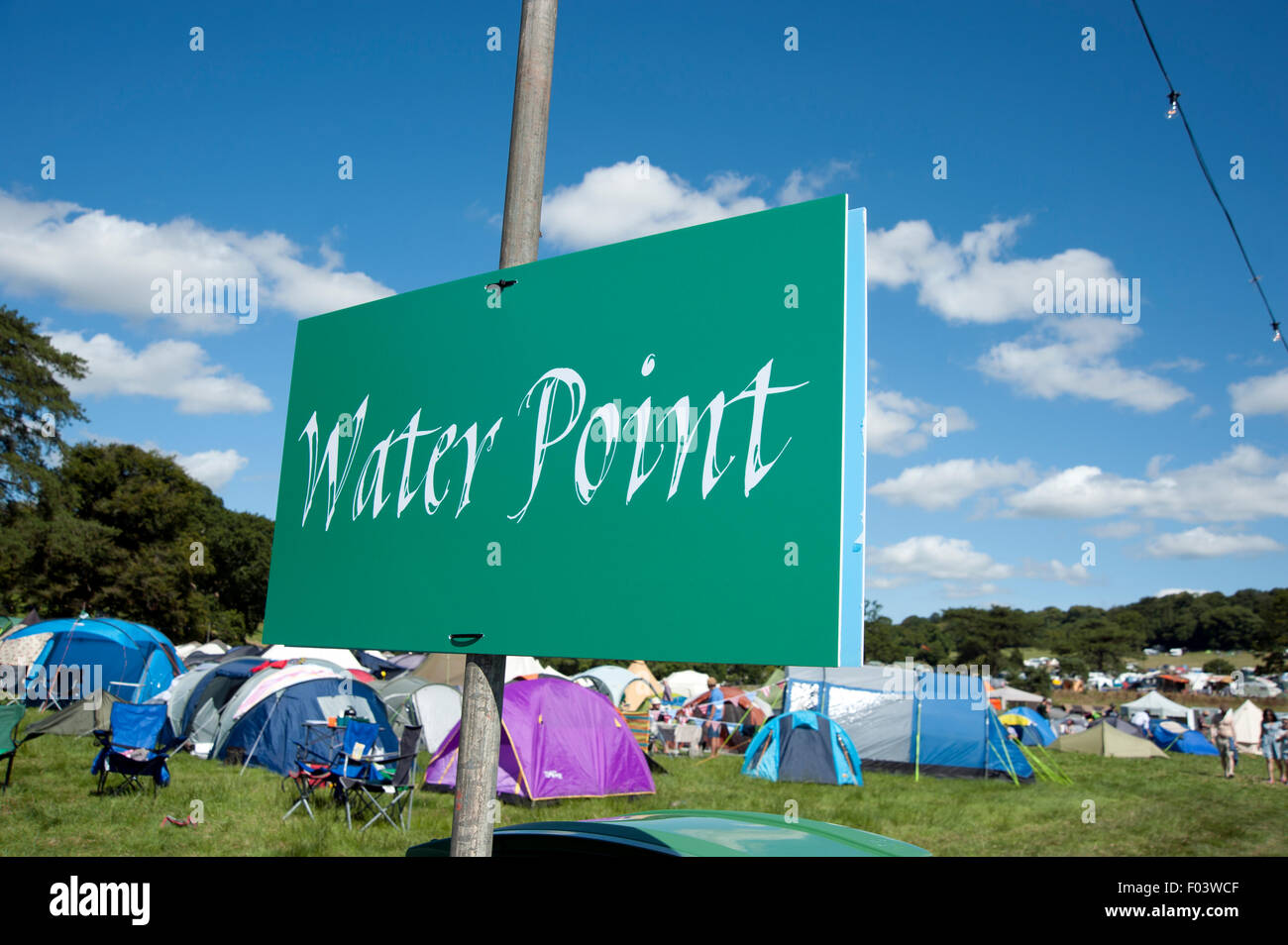 Water point sign in front of a campsite of tents with a blue sky fluffy ...