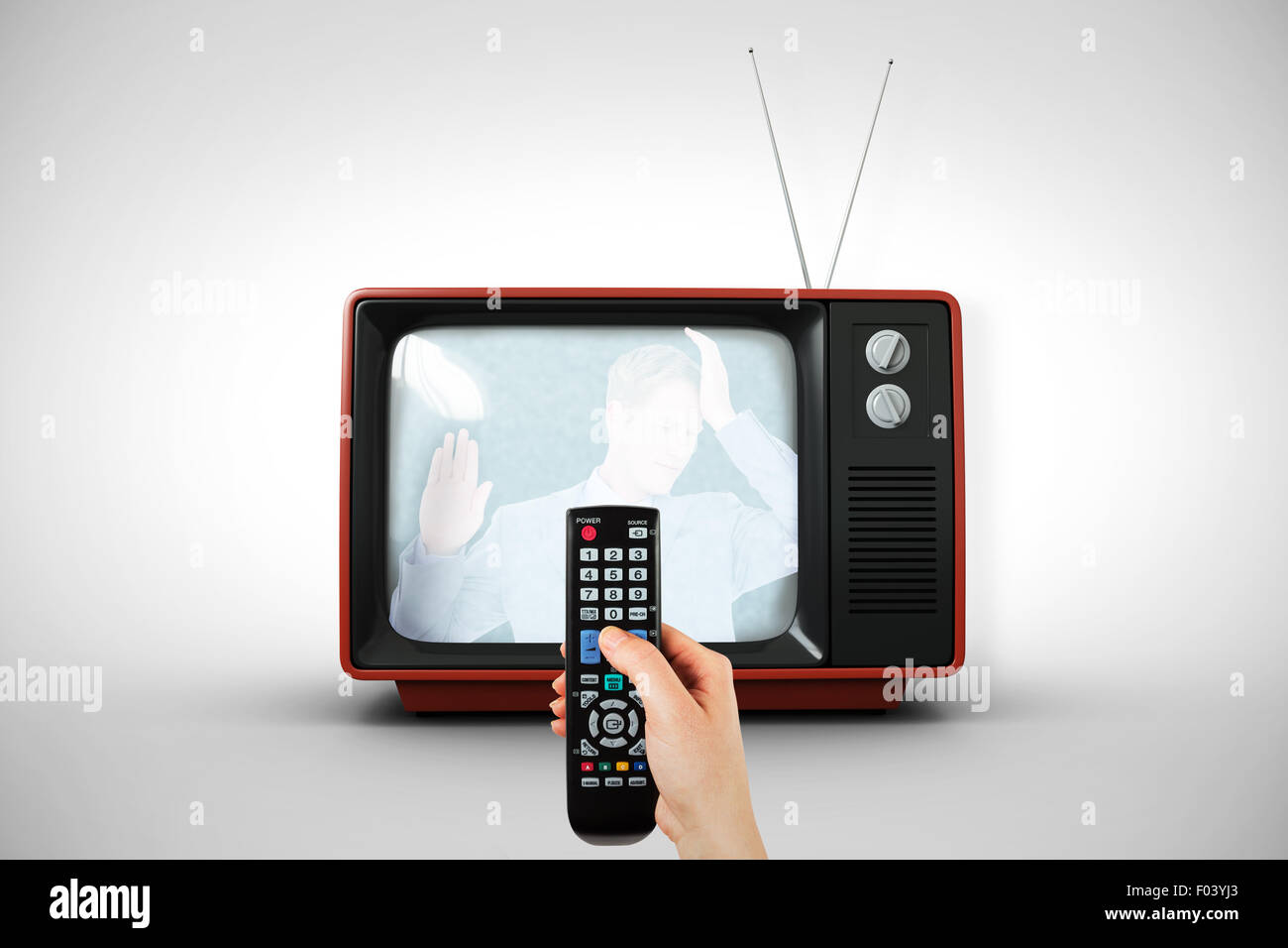 Composite image of hand holding remote control Stock Photo - Alamy