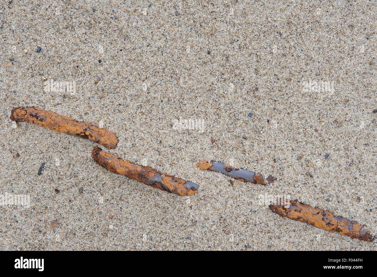 Rusty chain disappears under the sand of the beach Stock Photo - Alamy