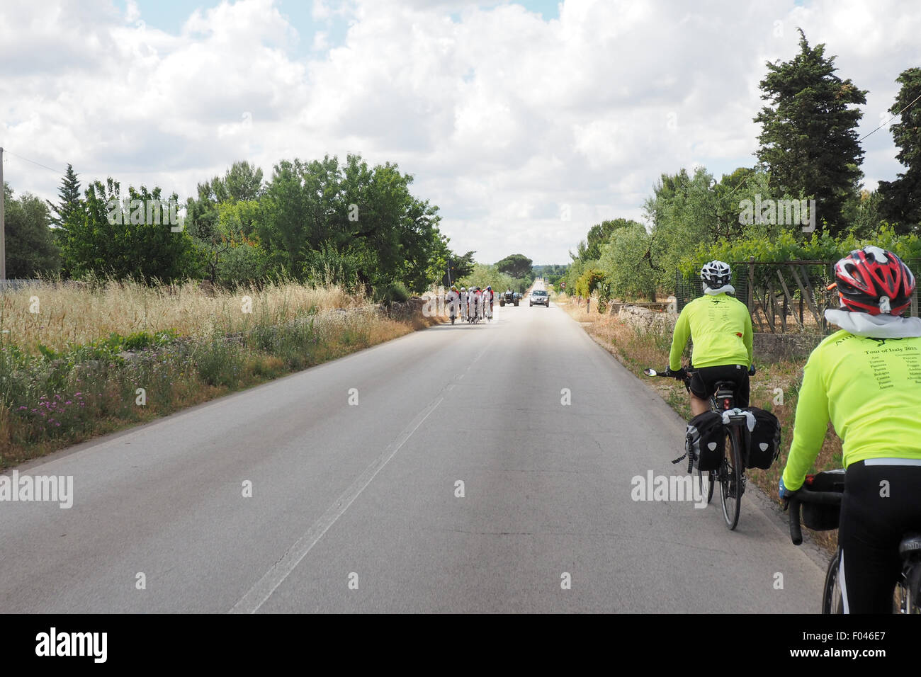 Two touring cyclists riding their bicycles on a country road with a ...