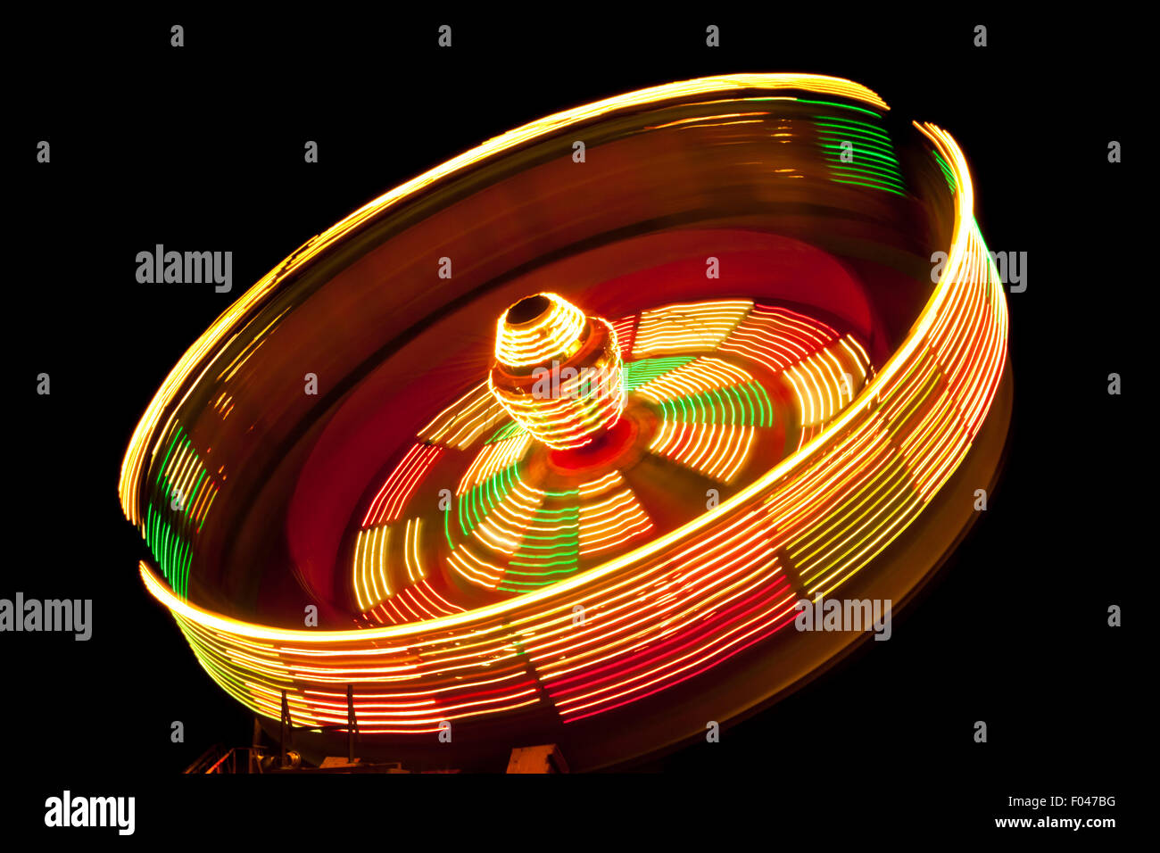 A spinning fair ride at night leaving a trail of circular lights on a ...
