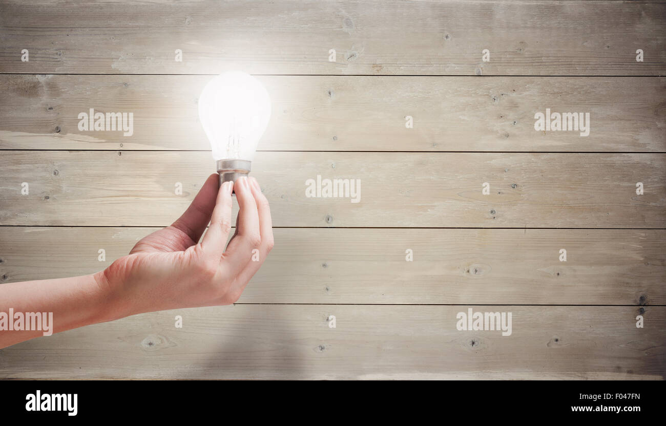 Composite image of hand holding light bulb Stock Photo - Alamy