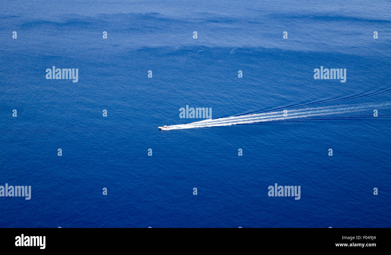 An isolated speed boat traveling across the ocean at high speed leaving ...
