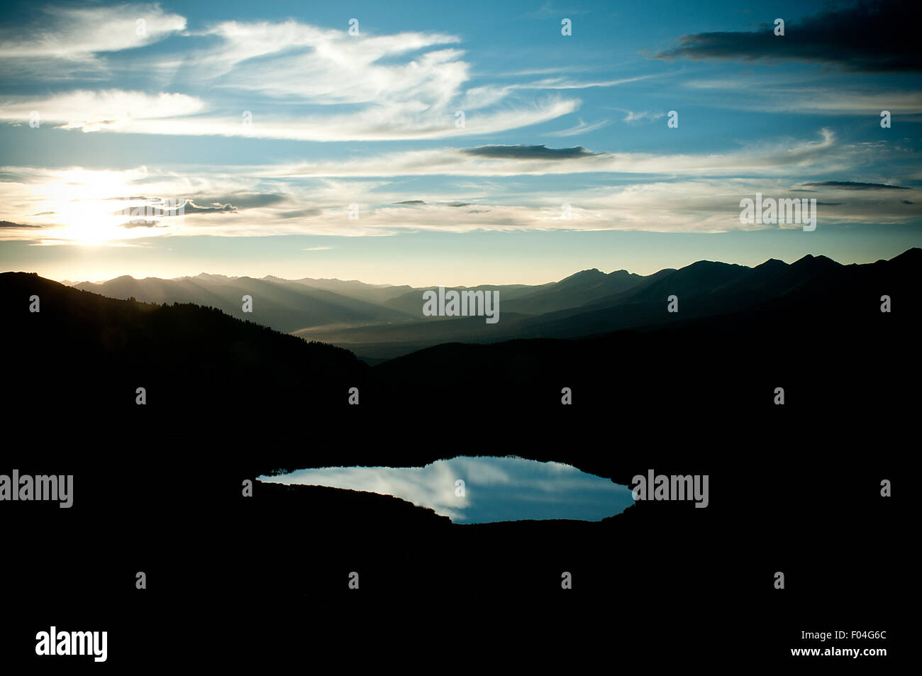 An alpine tarn reflects the evening light as sunset begins to wash over ...
