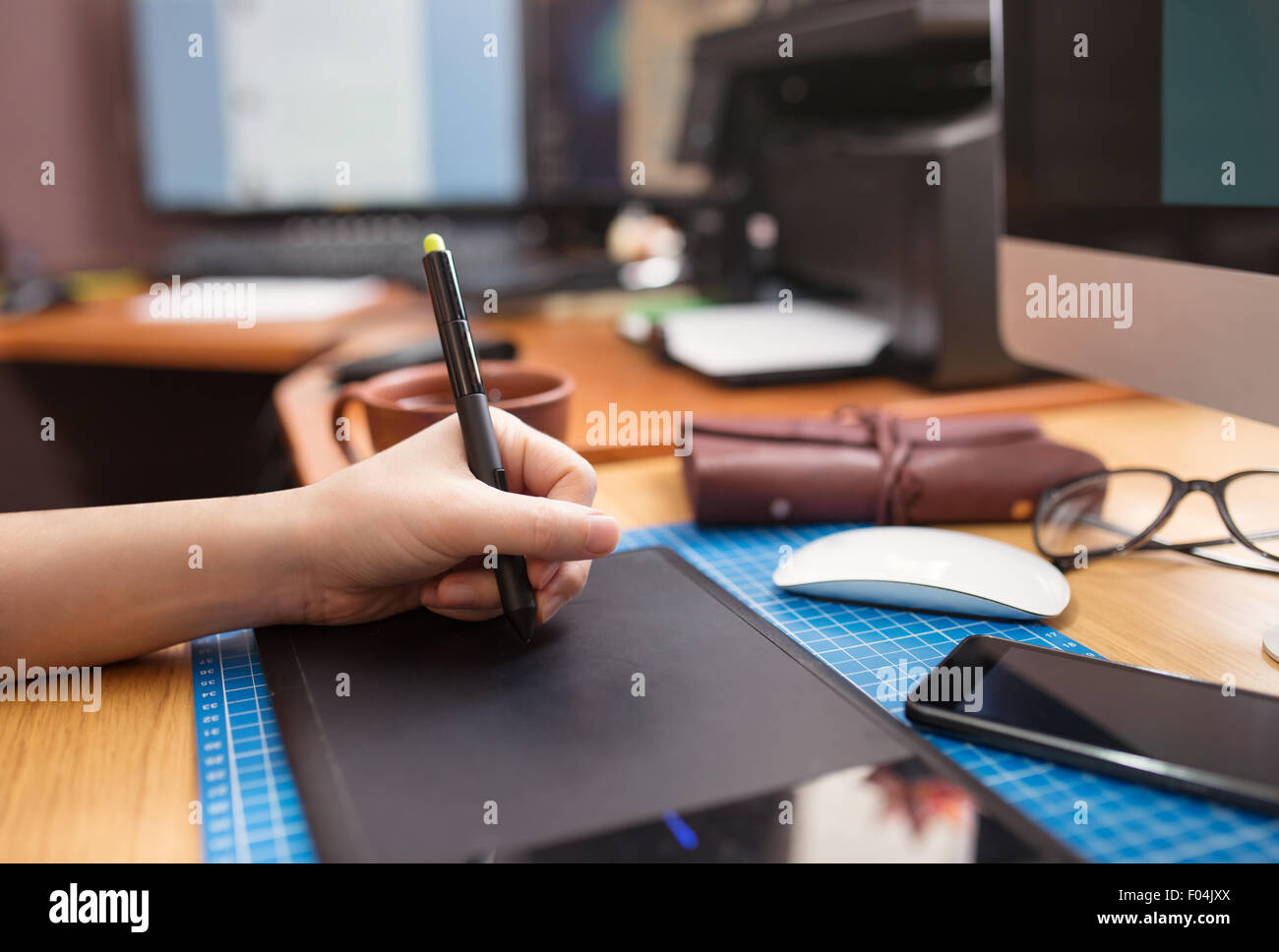 Close-up of a man's hand with a pen stylus, drawing on a graphic tablet ...