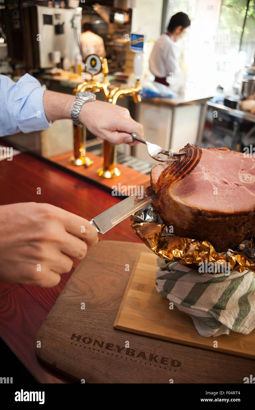 A member of staff slices a ''HoneyBaked Half Ham'' at the new Honey ...