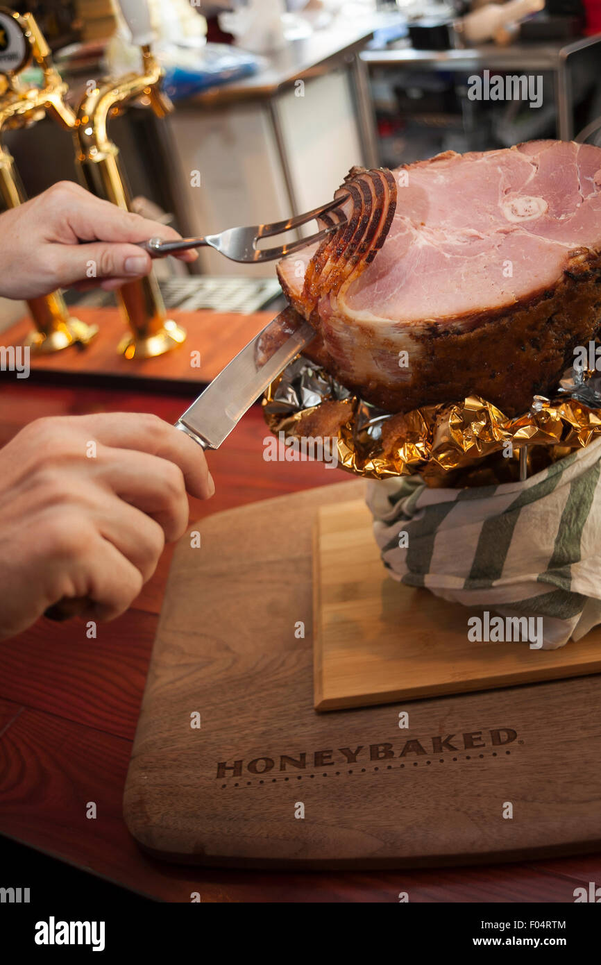 A member of staff slices a ''HoneyBaked Half Ham'' at the new Honey ...