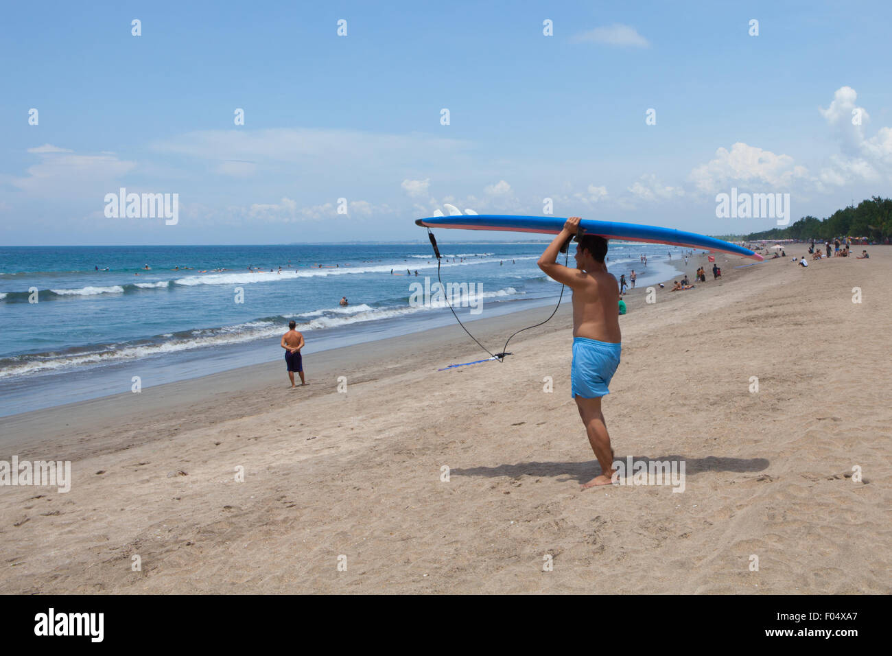 Man hauling surfboard at Kuta Beach, Bali Stock Photo - Alamy