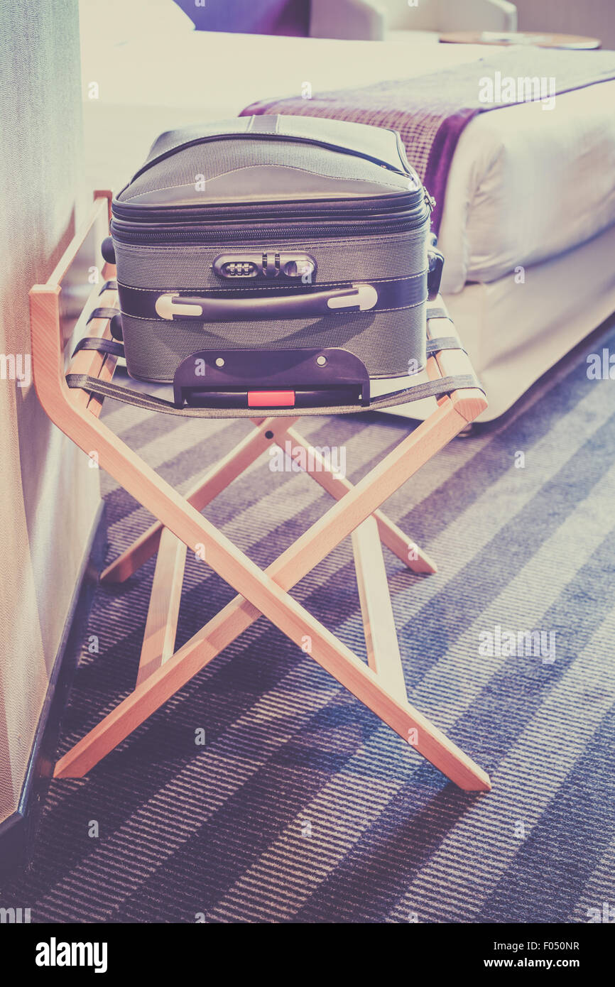 Hotel room with a suitcase on the luggage place and the bed. Filtered ...