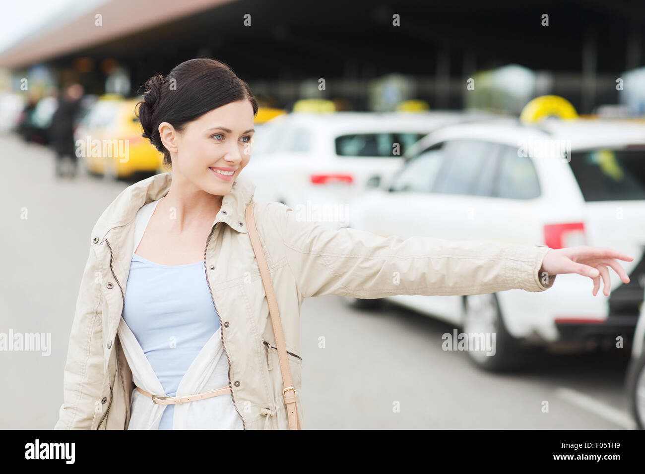smiling young woman waving hand and catching taxi Stock Photo - Alamy