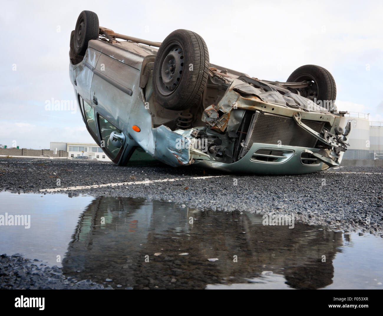 car turned upside-down after road collision and reflection in the water ...