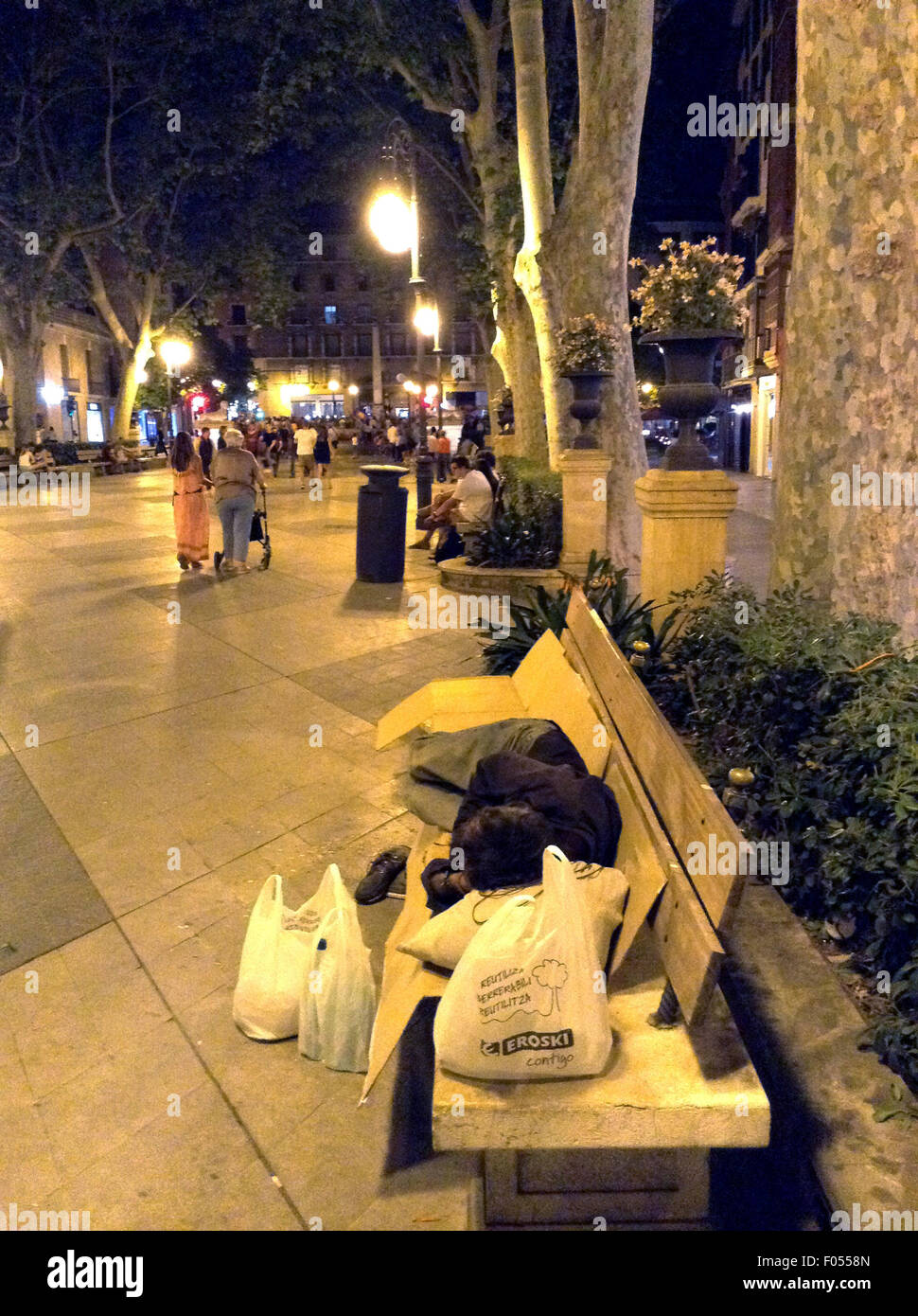 A homeless person sleeps on a bench close to the esplanade 'Passeig del ...