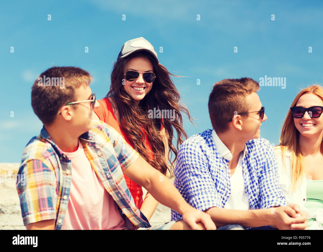 group of smiling friends sitting on city street Stock Photo - Alamy