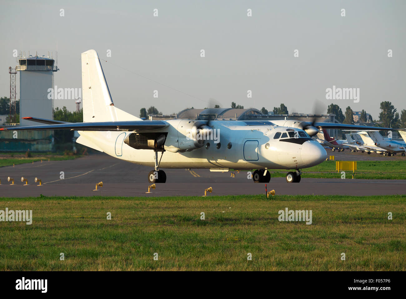White propeller turboprop plane on the runway in the airport on sunset ...