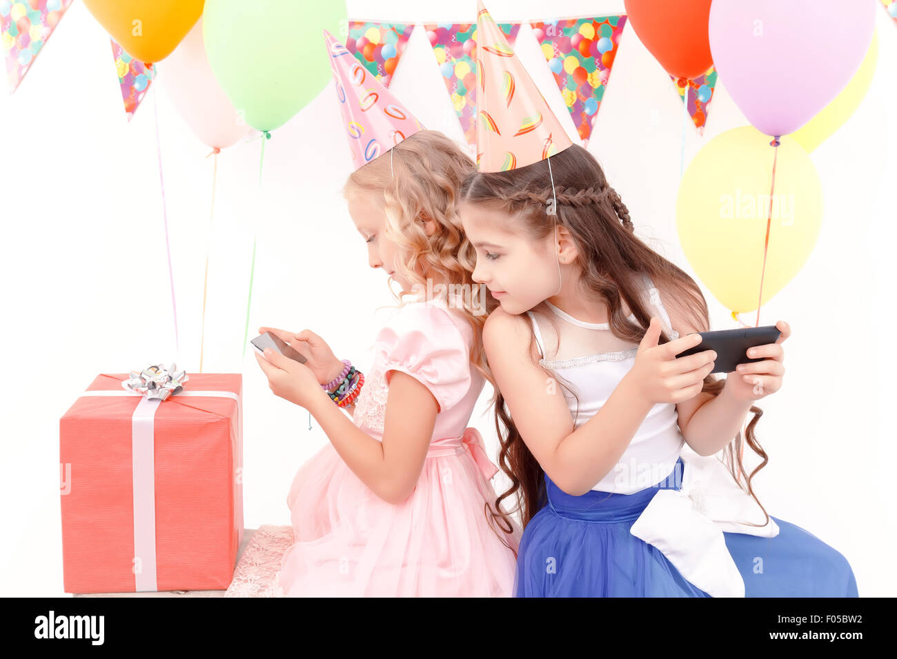 Two girls with mobile phone during birthday party Stock Photo - Alamy