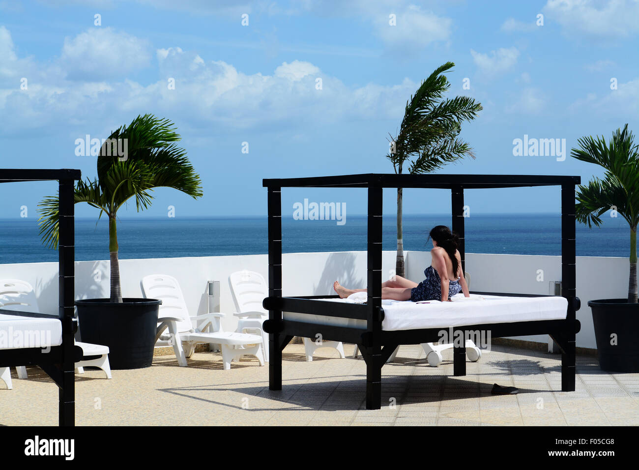Young woman sitting down on a tanning bed looking into the ocean Stock ...