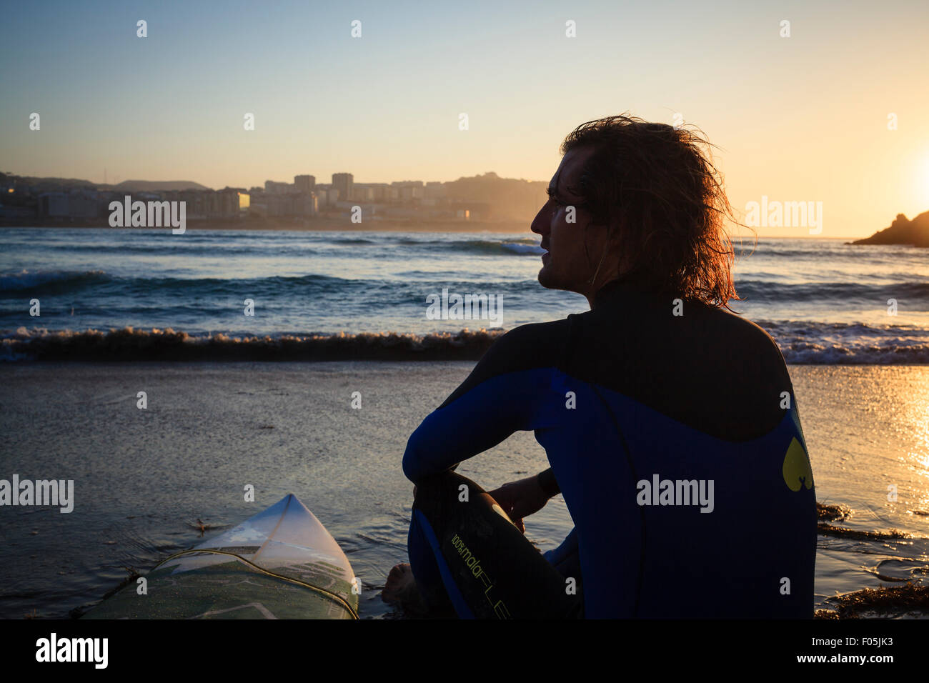 Surfer Pablo Macineira sitting on beach with surfboard. Orzan Beach. A ...